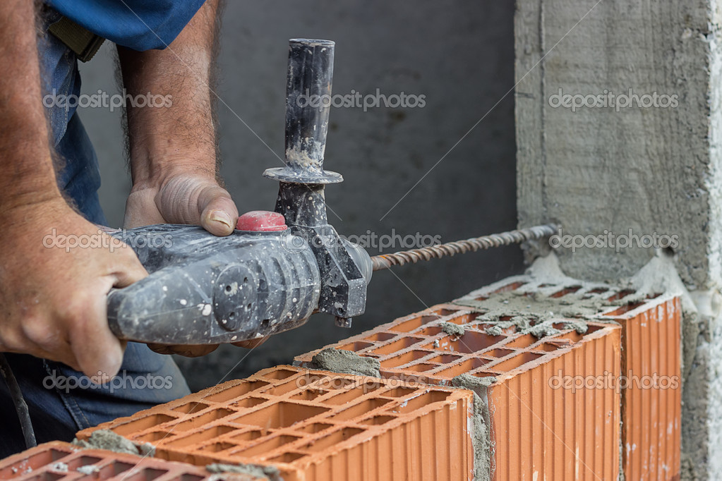 Trabajador de la construcción utiliza taladro para hacer agujeros en ...