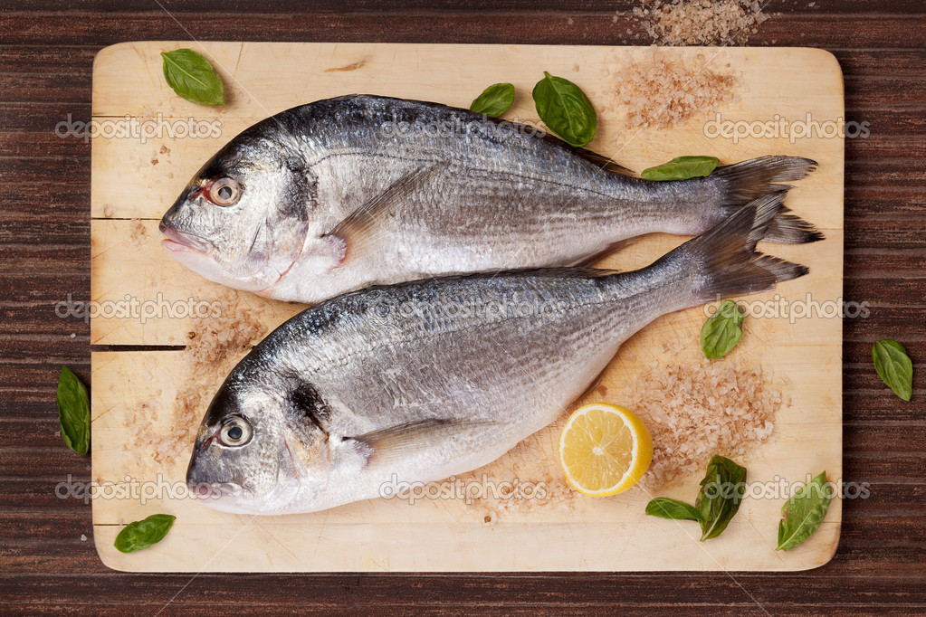 Raw fish with ingredients on wooden chopping board. Stock Photo by ...