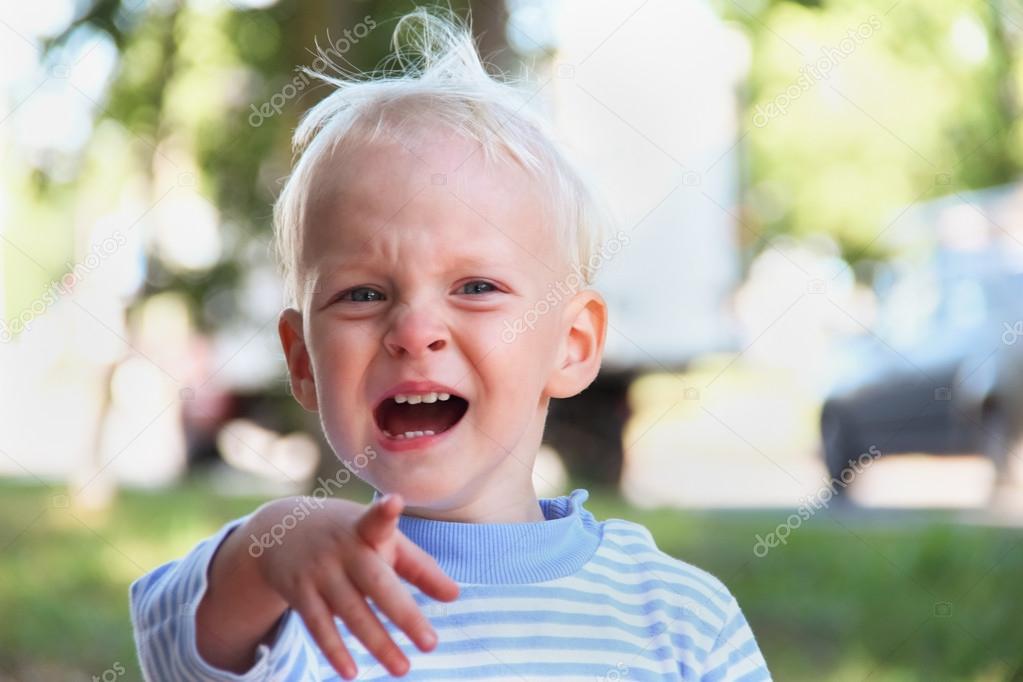 Little boy is crying and pointing his fingers forward asking to give ...