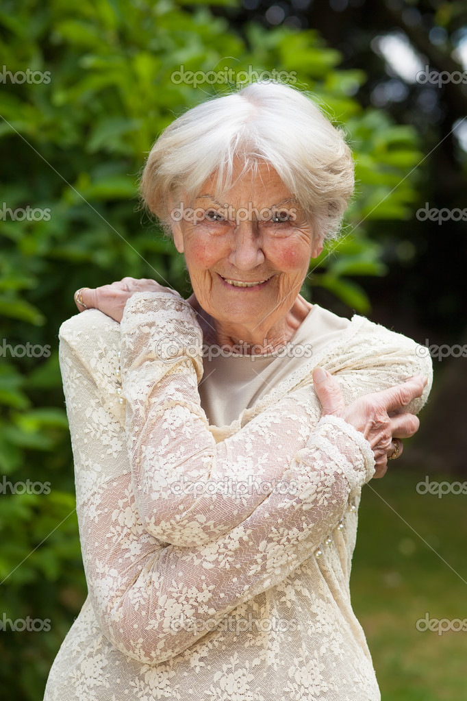Elderly lady posing in a green garden — Stock Photo © belahoche #34294565