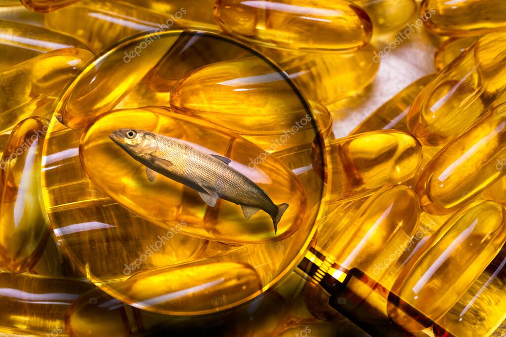 La lupa se acerca a la cápsula omega3 con un pez vivo dentro. Concepto ...