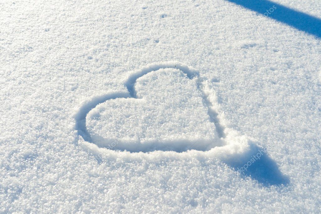Una mano dibujó la forma del corazón en la nieve fresca.Vista superior ...