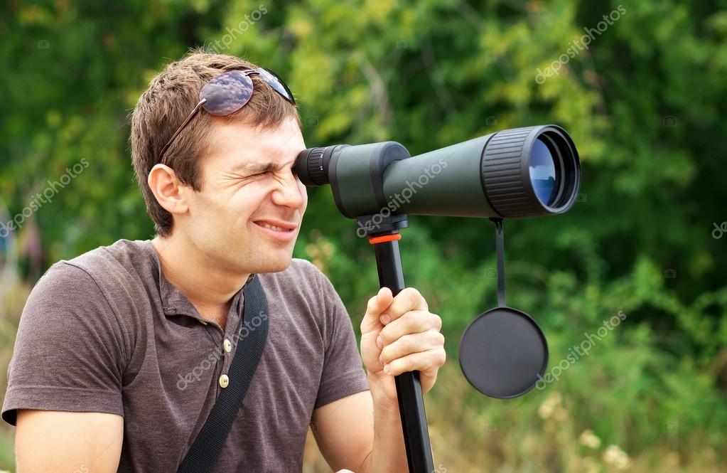 Man who is watching in spotting scope. Positive man looking thro Stock ...
