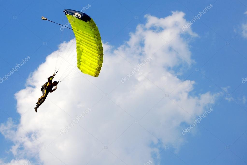 Parachuter descending with a parachute against blue sky — Stock Photo ...