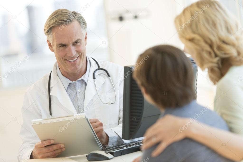 Doctor explicando informe a hijo y madre en la clínica 2023