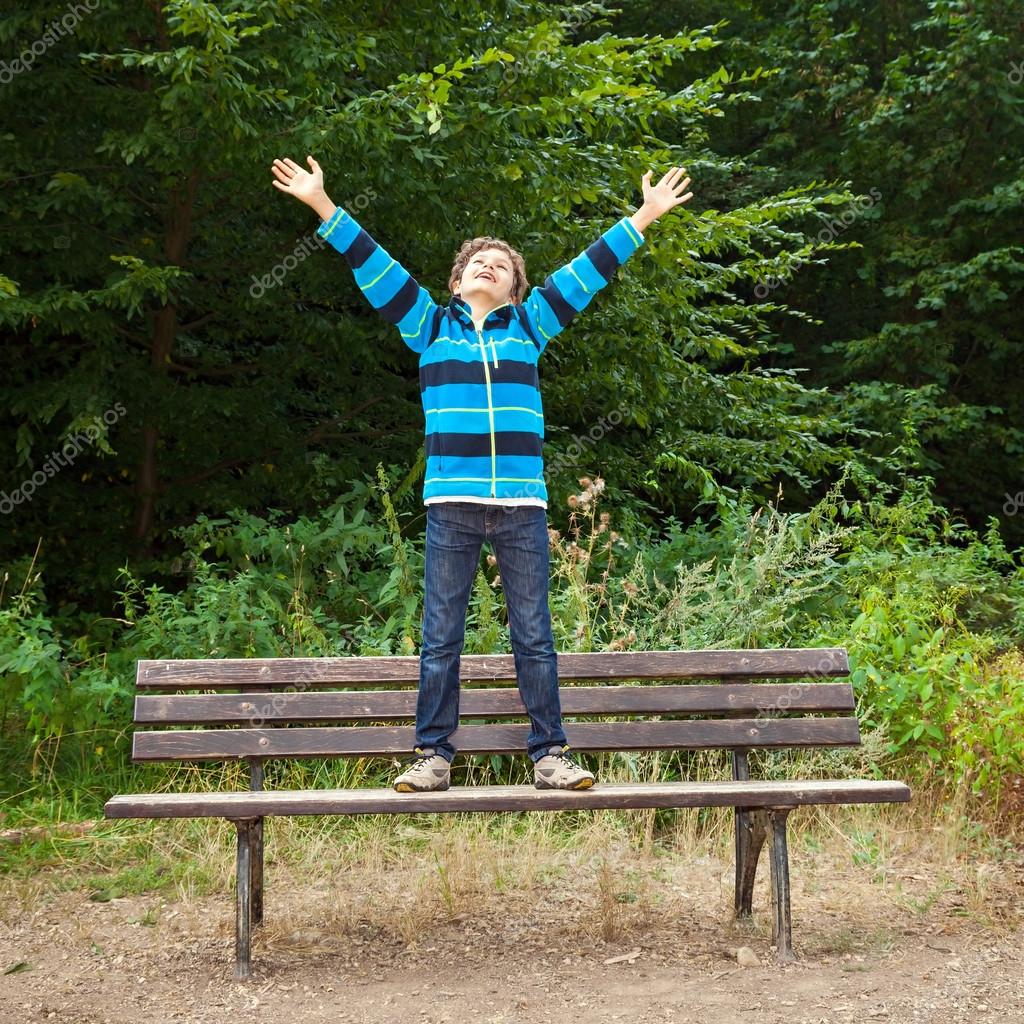 Boy standing on a bench in a forest — Stock Photo © peterfuchs #31048667