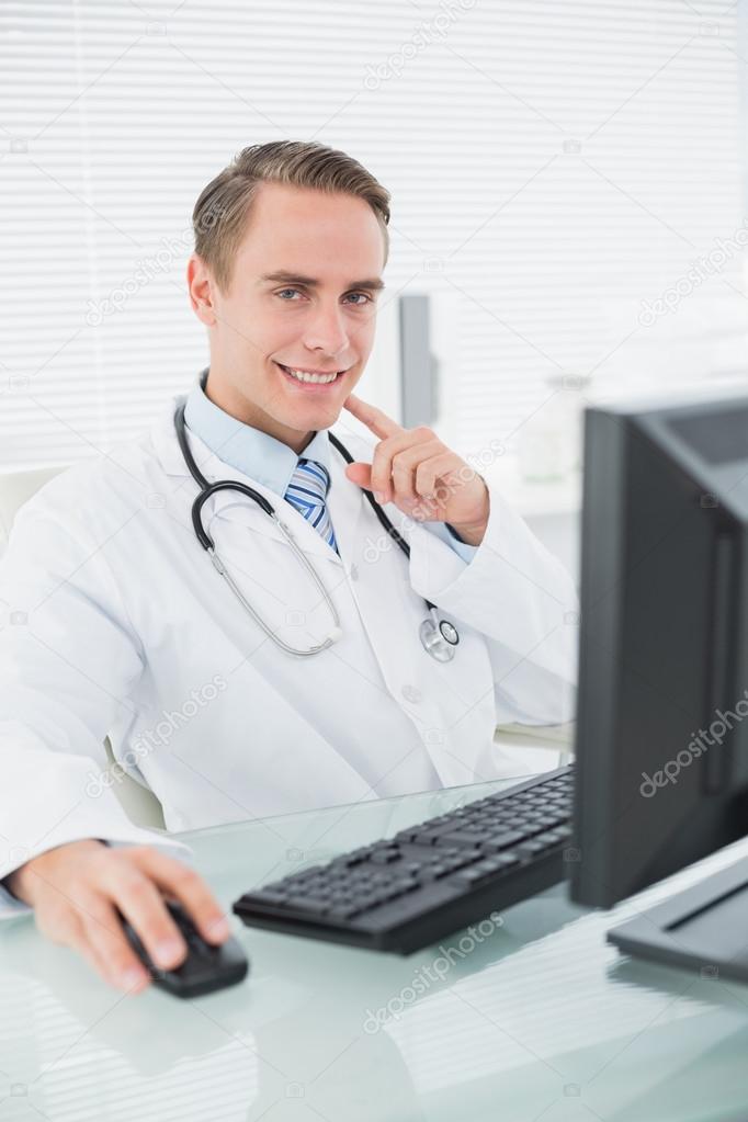 Smiling male doctor with computer at medical office — Stock Photo ...