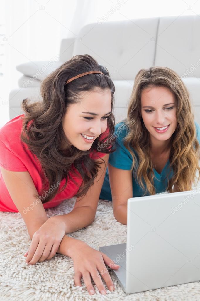 Two young female friends using laptop at home Stock Photo by ...