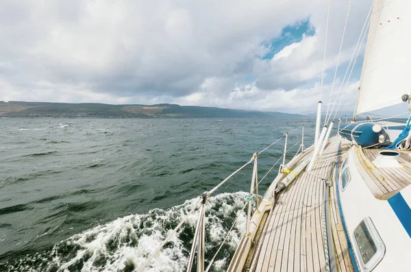 Sloop rigged modern yacht with wooden teak deck sailing near the rocky ...