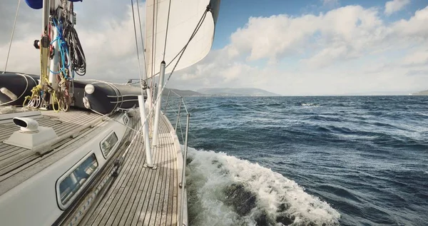 Sloop rigged modern yacht with wooden teak deck sailing on a cloudy day ...