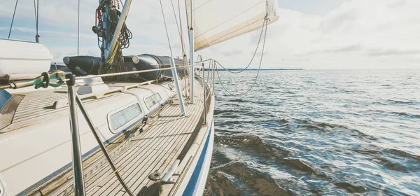 Sloop rigged modern yacht with wooden teak deck sailing near the rocky ...