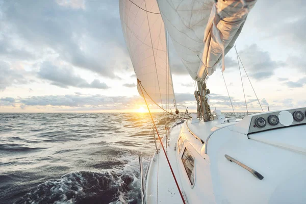 Yacht sailing in an open sea at sunset. Close-up view of the deck, mast ...
