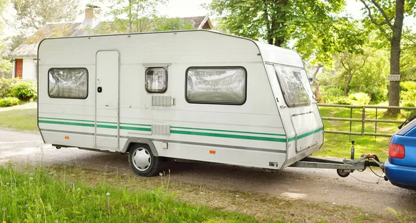 White caravan trailer and a car parked on the rural road under the ...