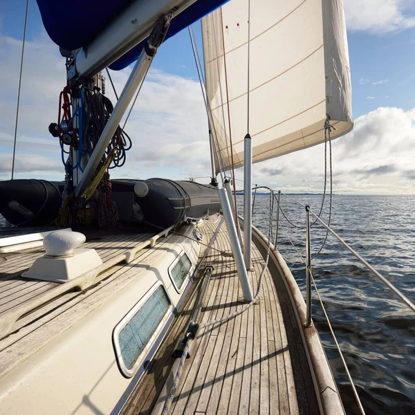Sloop rigged modern yacht with wooden teak deck sailing on a cloudy day ...