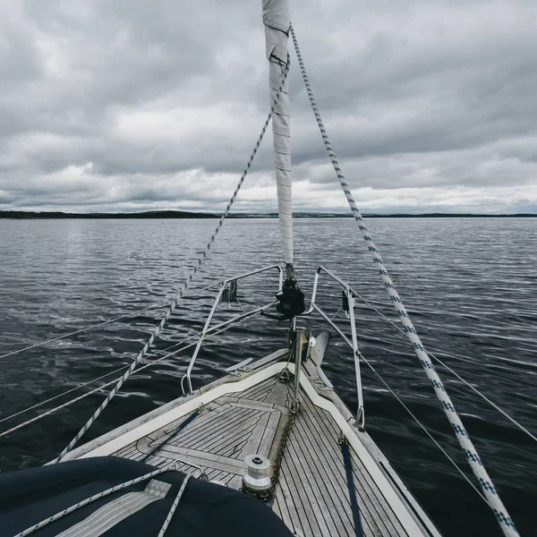 Sloop rigged modern yacht with wooden teak deck sailing near the rocky ...