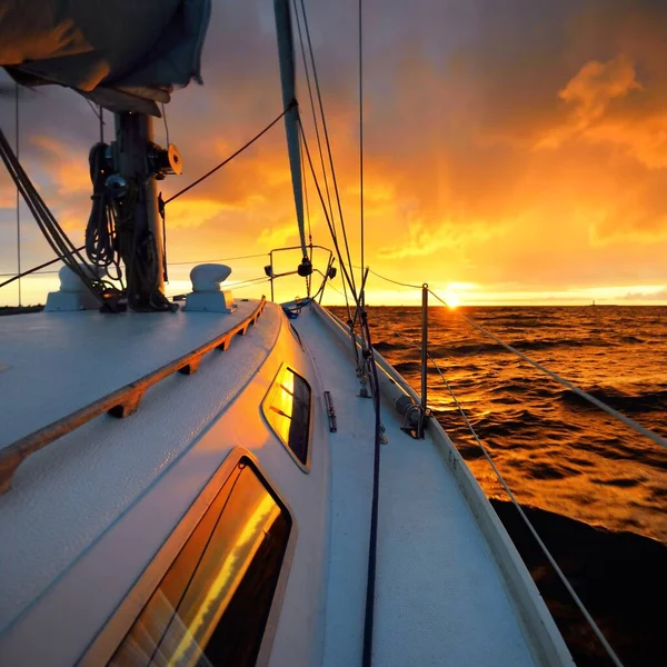 White yacht sailing in an open sea at sunset. A view from the deck to ...