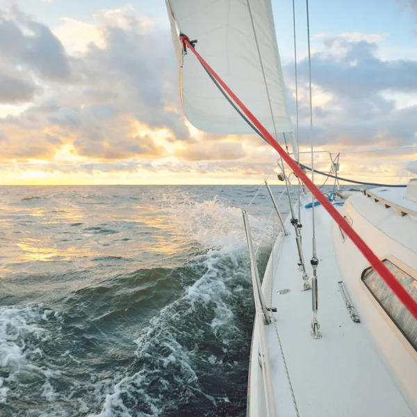 Yacht sailing in an open sea at sunset. Close-up view of the deck, mast ...