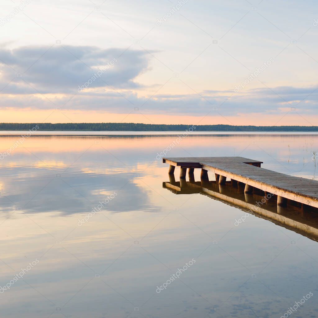 Forest lake (river) at sunset. Wooden pier. Glowing clouds, symmetry ...