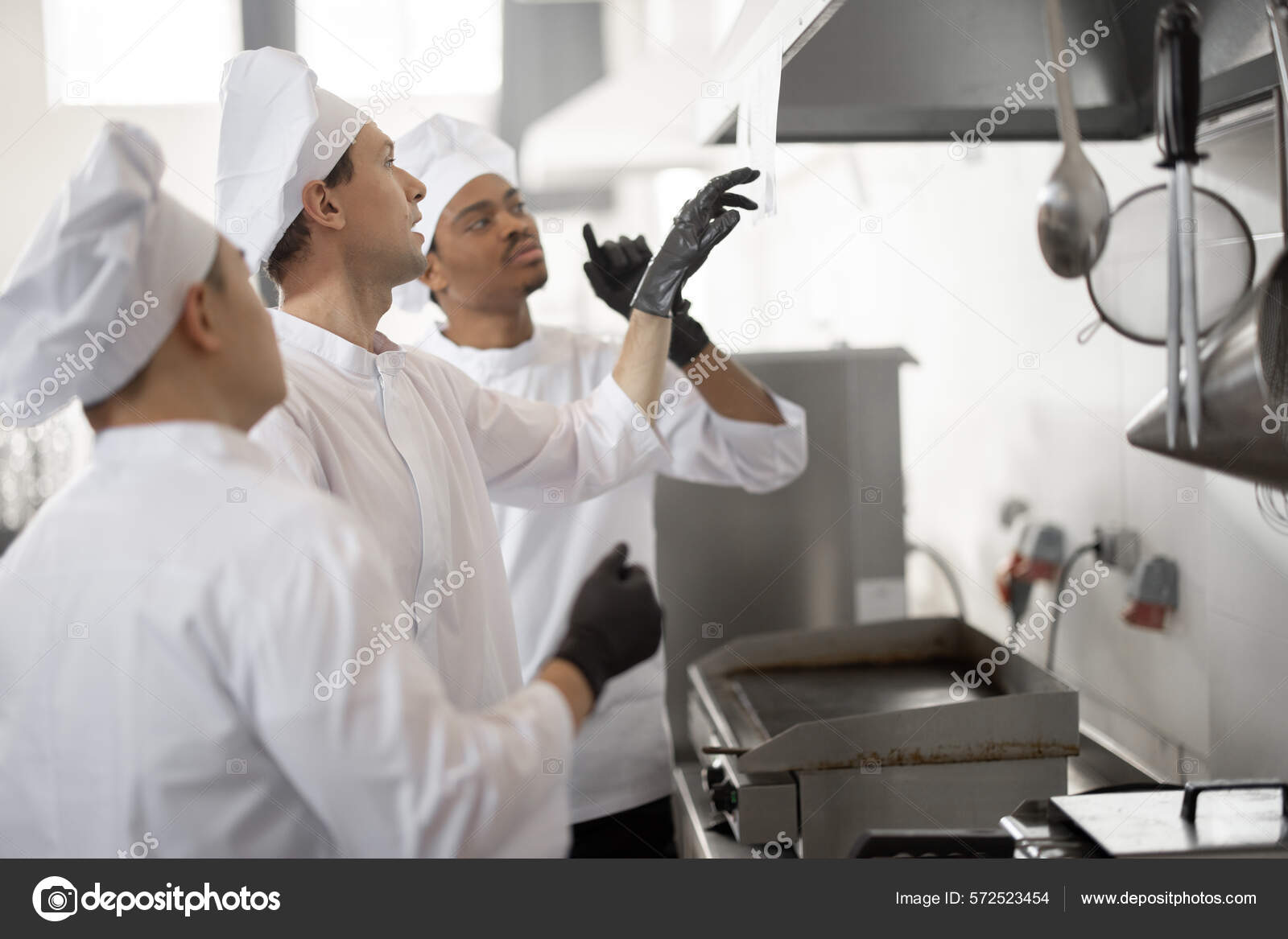 Chefs look on printed checks with orders while cooking in the ...