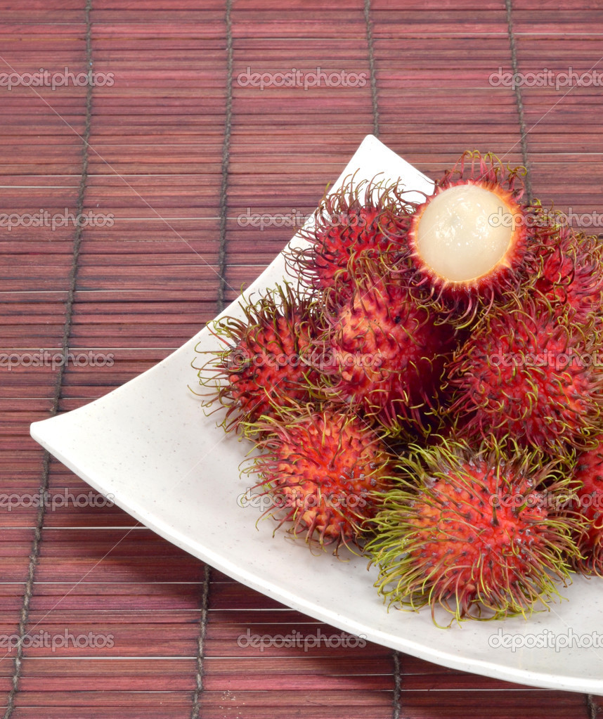 Tropical fruits rambutan with plate on bamboo mat Stock Photo by ...