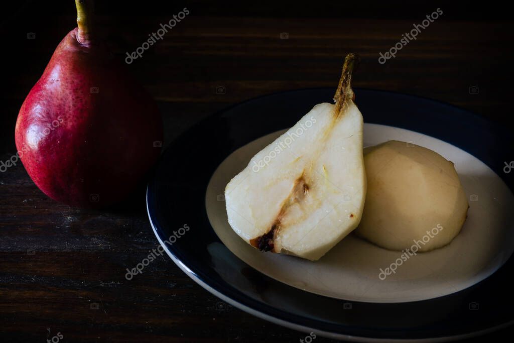 Vista alta de una pera roja sin pelar y dividida a la mitad en un plato ...