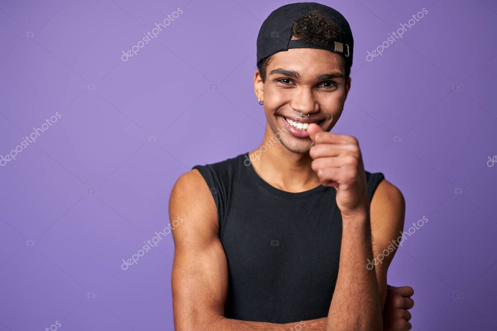 Retrato de un joven moreno sonriente con camiseta y gorra negra. Feliz ...