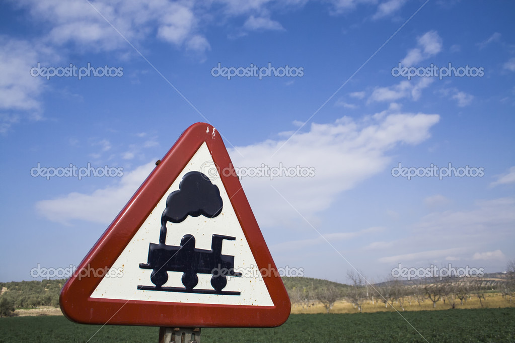 Warning sign worn of level crossing without barriers, blue sky with ...
