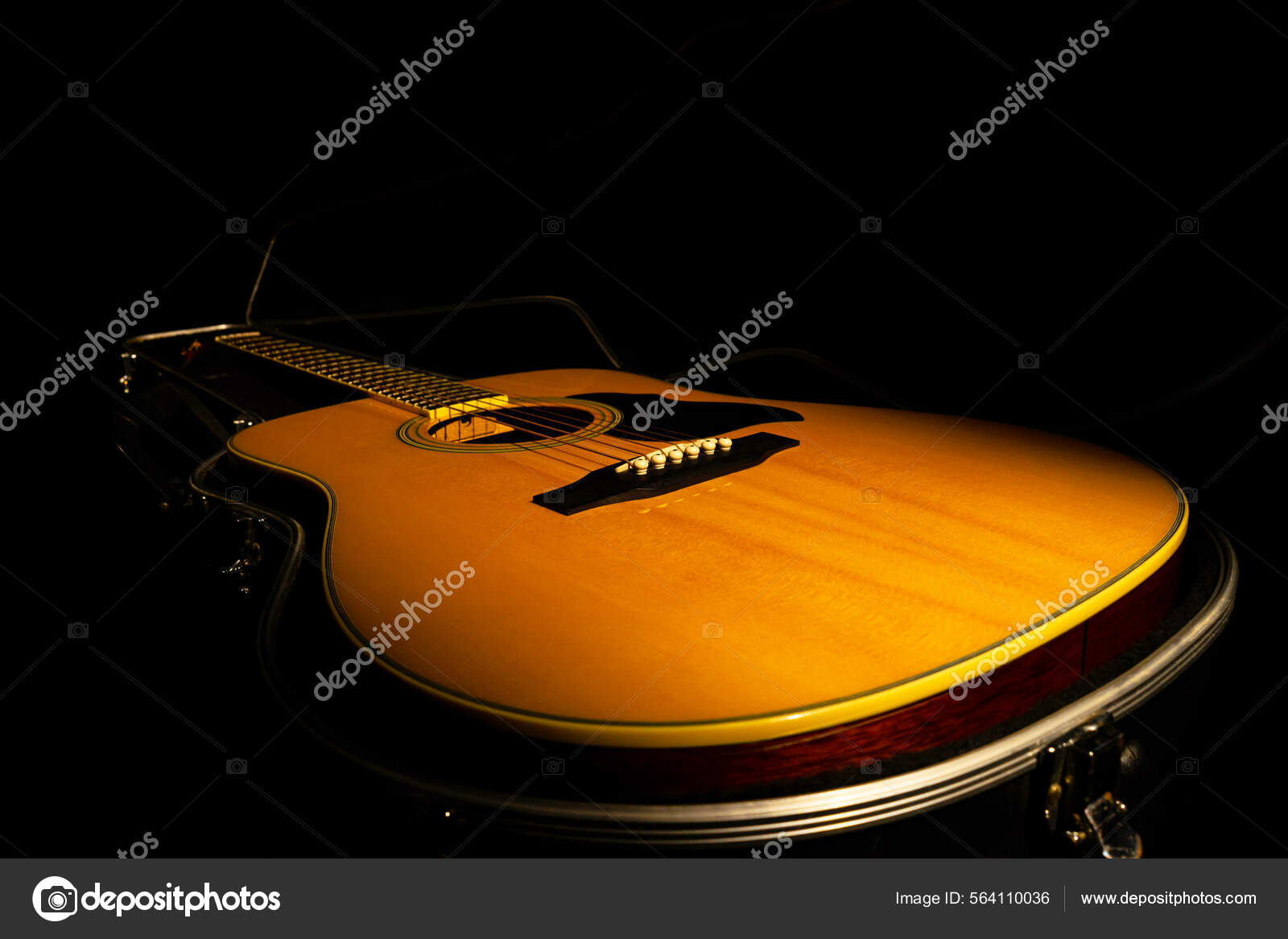 Yellow acoustic guitar lying in a hard case in the dark on a black ...