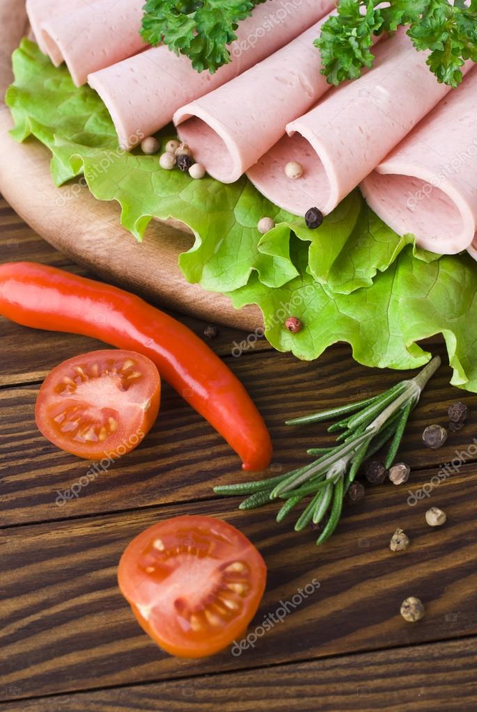 Rodajas de jamón fresco con lechuga y tomate cherry en la tabla de ...