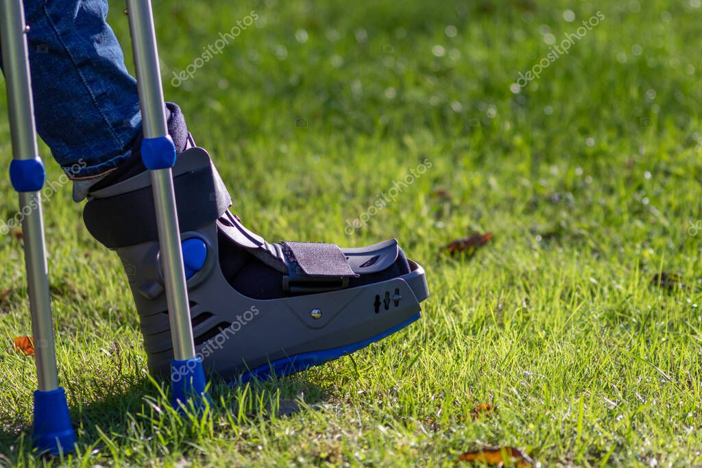 Niño con pie roto y zapato ortopédico o caminante después de fractura ...