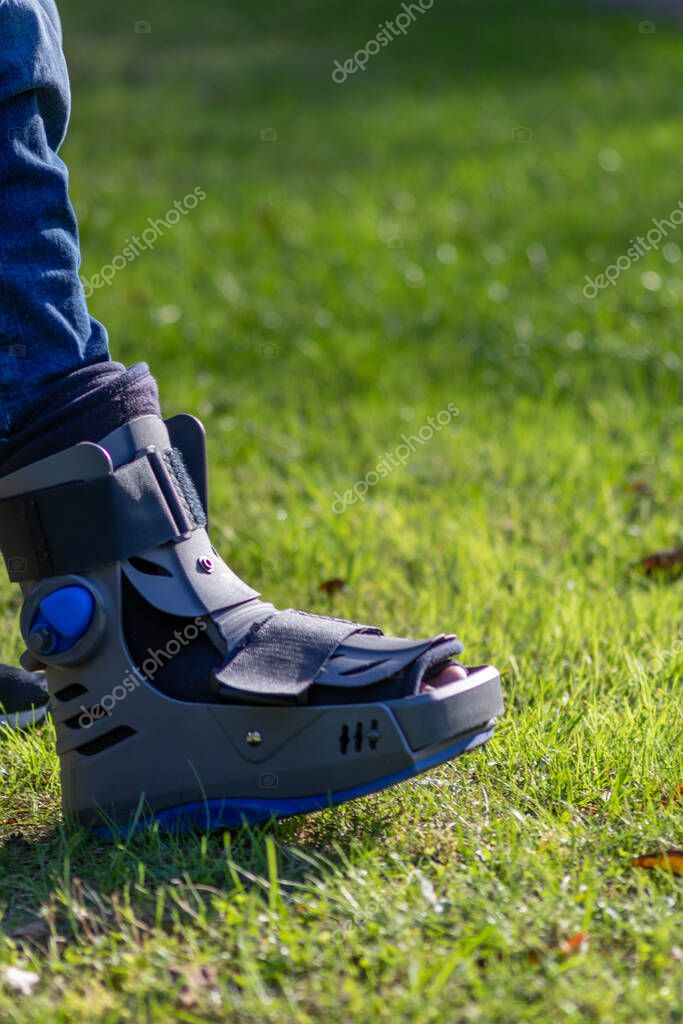 Niño con pie roto y zapato ortopédico o caminante después de fractura ...