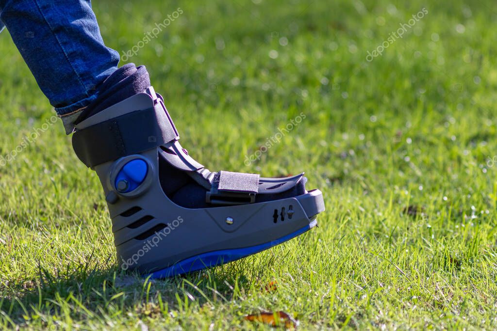 Niño con pie roto y zapato ortopédico o caminante después de fractura ...