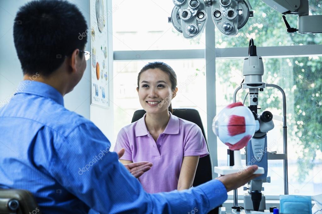 Optometrist discussing with young woman in his clinic — Stock Photo ...