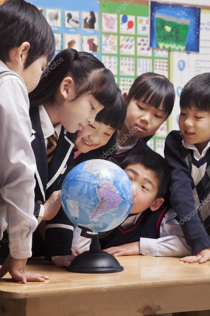 Schoolchildren looking at a globe in the classroom — Stock Photo ... Schoolchildren looking at a globe in the classroom — Stock Photo ...