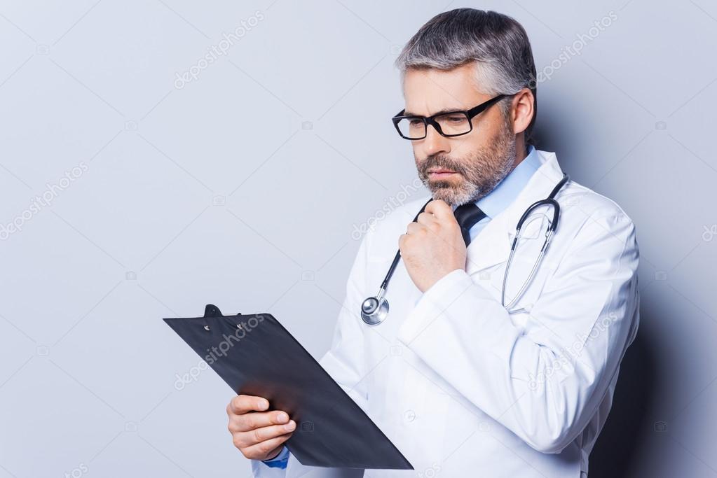 Doctor looking at his clipboard Stock Photo by ©gstockstudio 49312721