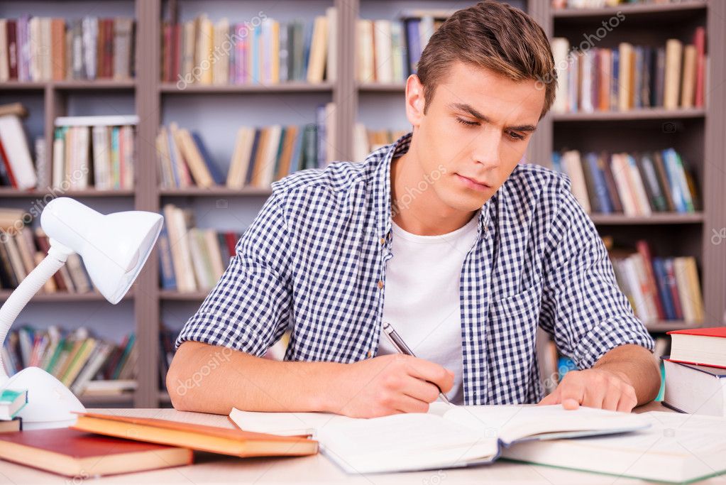 Confident young man making research in library — Stock Photo ...