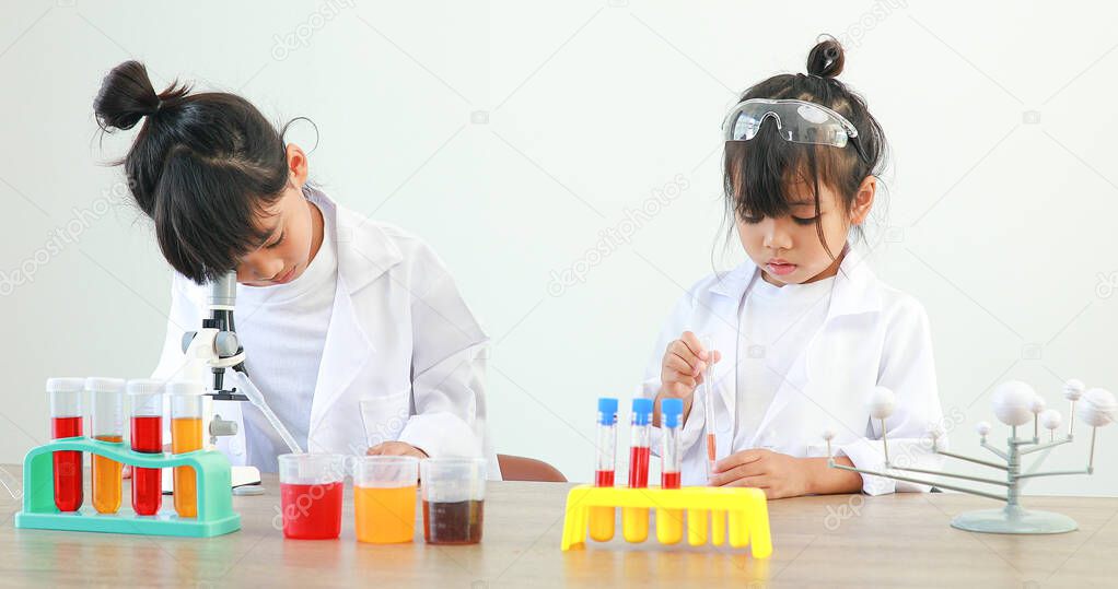 Niña asiática lindo poco estudiante aprendizaje investigación y haciendo un experimento químico ...