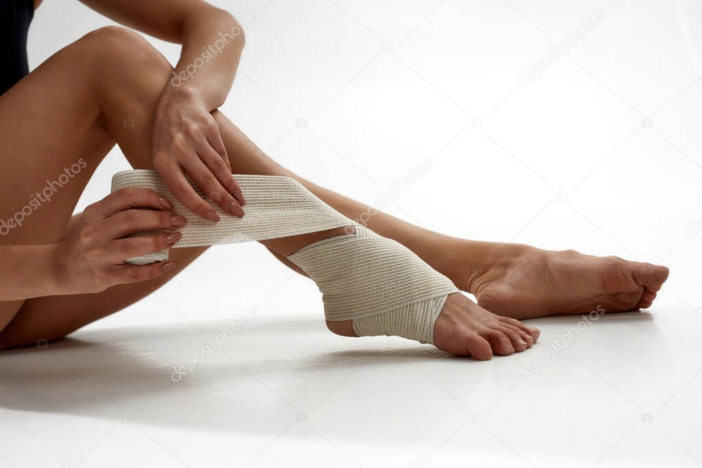 Parcial de la mujer que pone vendaje elástico en la pierna 2023