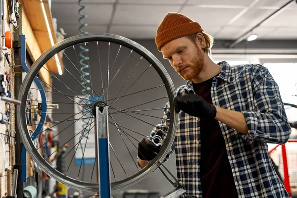 Young cycling worker checking bicycle wheel spoke - Stock Image ...