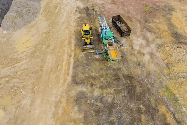 Construction heavy equipment is grading the land, moving out clay soil ...