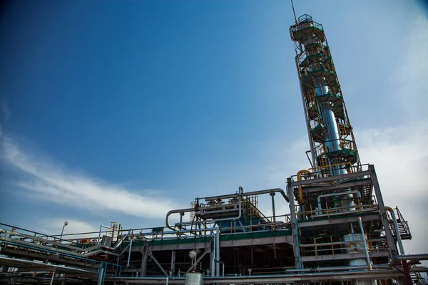Grey distillation tower (column) at bright sun on blue sky with clouds ...