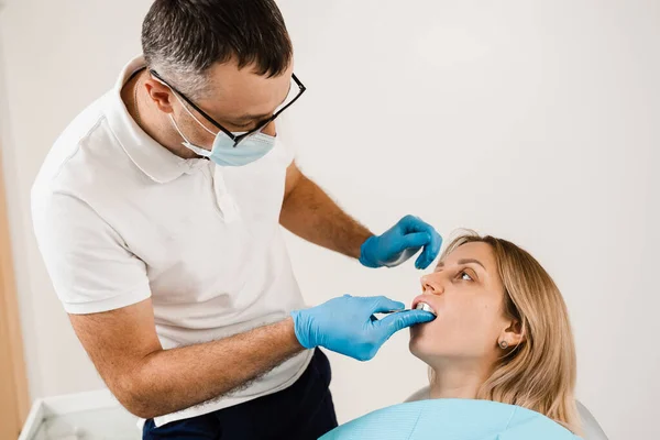 Doctor inserts impression tray and making cast of teeth to patient in ...