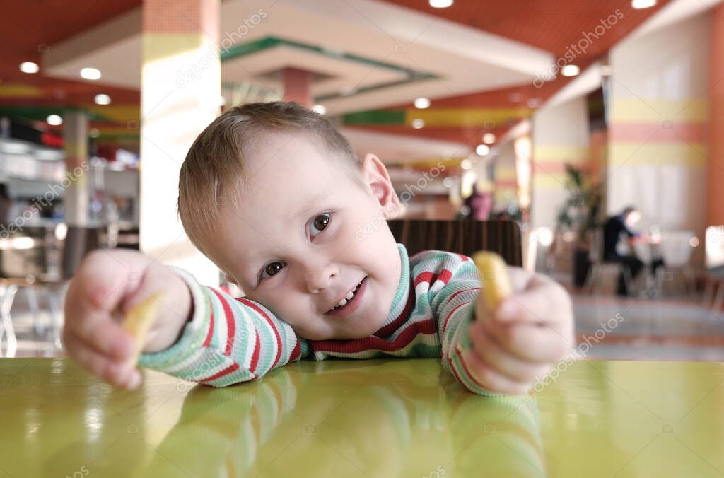 El chico está aburrido en un café, juega a las papas fritas 2024