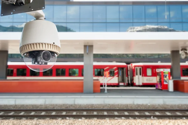 CCTV camera or surveillance operating in train station with people in ...
