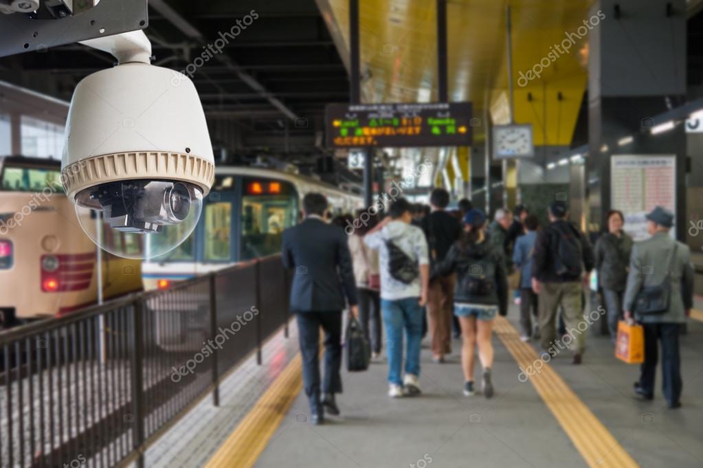 CCTV camera or surveillance operating in train station with people in ...