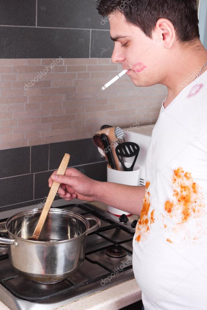 Handsome young man cooking and smoking — Stock Photo © olgamarc #42423071