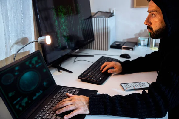 Hooded Man hacker using laptop, computer PC and mobile phone to digital ...