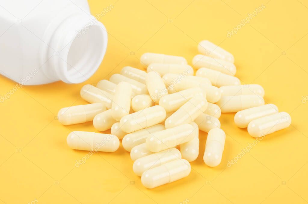 Cápsulas de medicina farmacéutica amarilla sobre fondo amarillo. Frasco ...