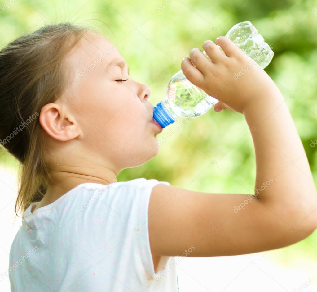 Cute girl drinks water from a plastic bottle Stock Photo by ©julaszka 50340115
