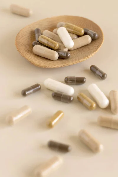 Mix of medical capsules in a bowl on light beige close up. Preventive ...